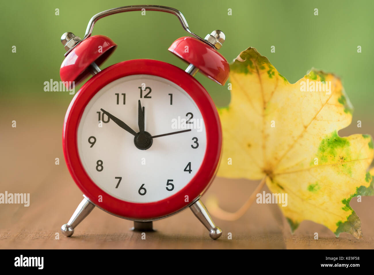 Red vintage clock and mable leaf. Autumn time change Stock Photo - Alamy
