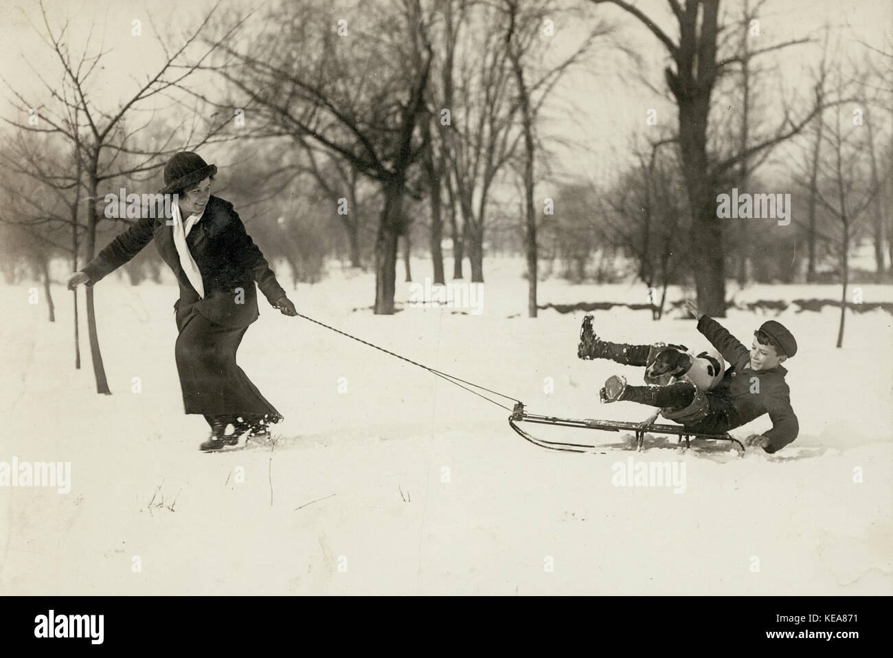 Woman pulling a child on a sled in an unidentified park Stock Photo - Alamy