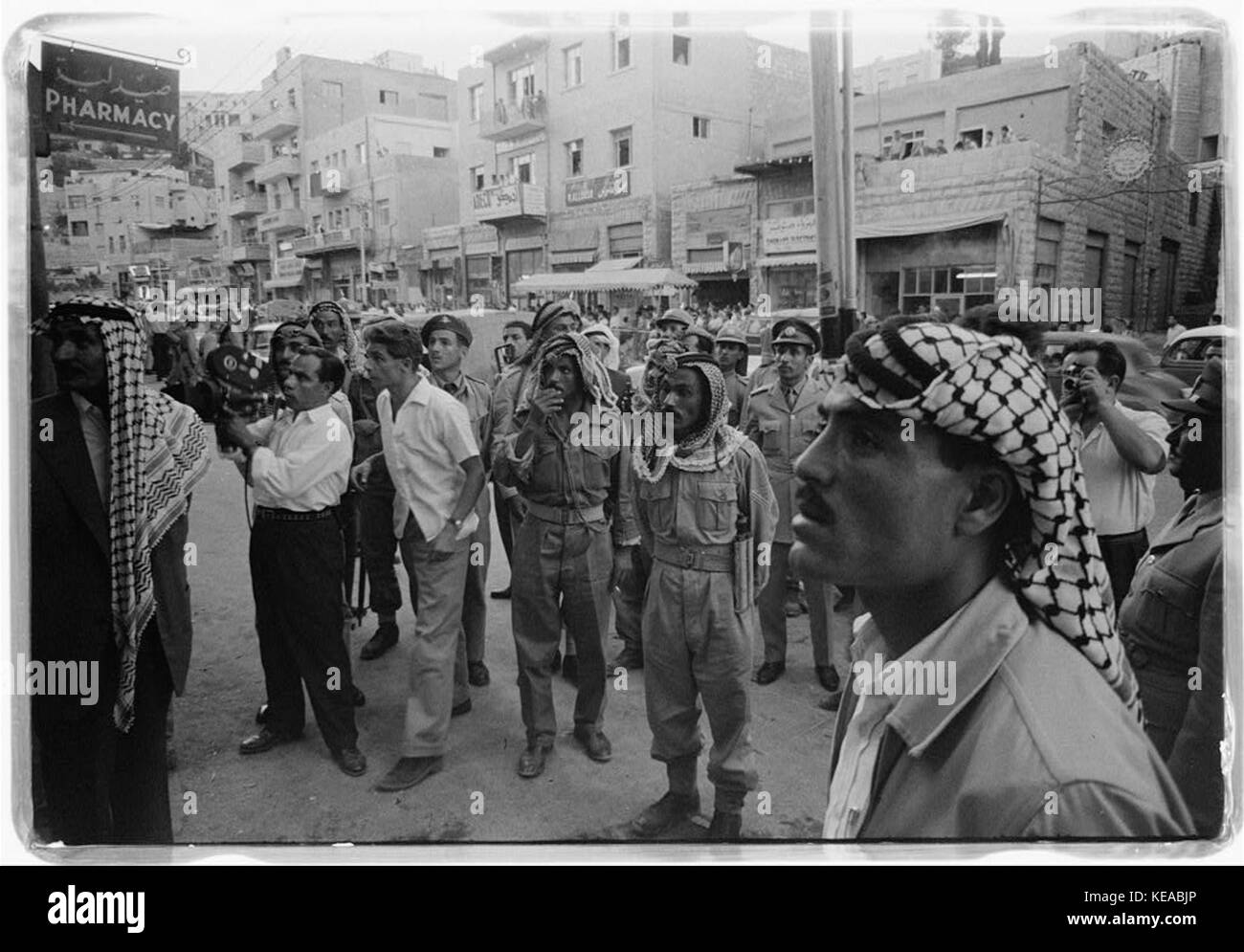 Crowds in downtown Amman watching a news report about King Faisal's ...