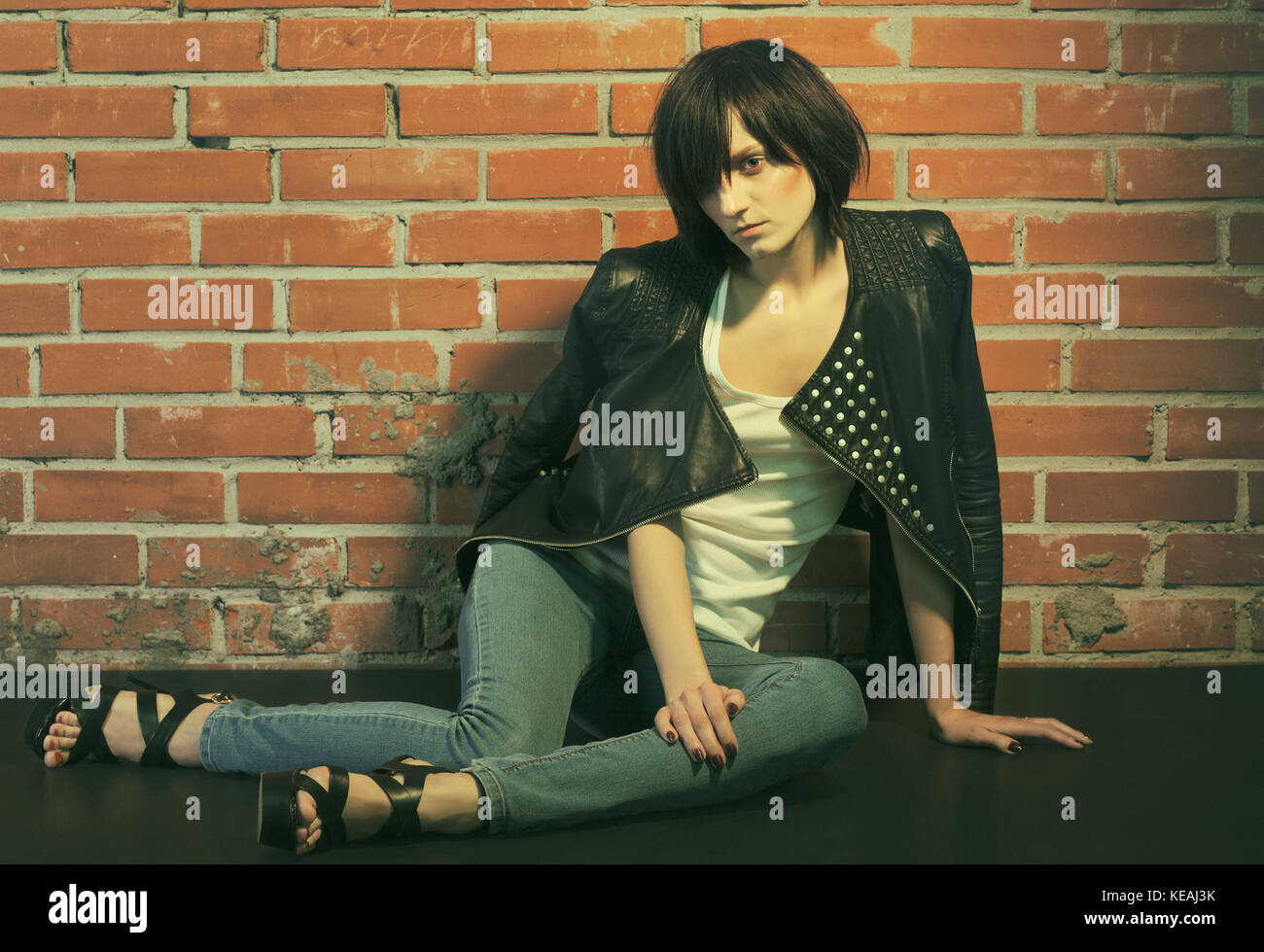 Androgyny female model in Heroin chic style near brick wall. Old style ...