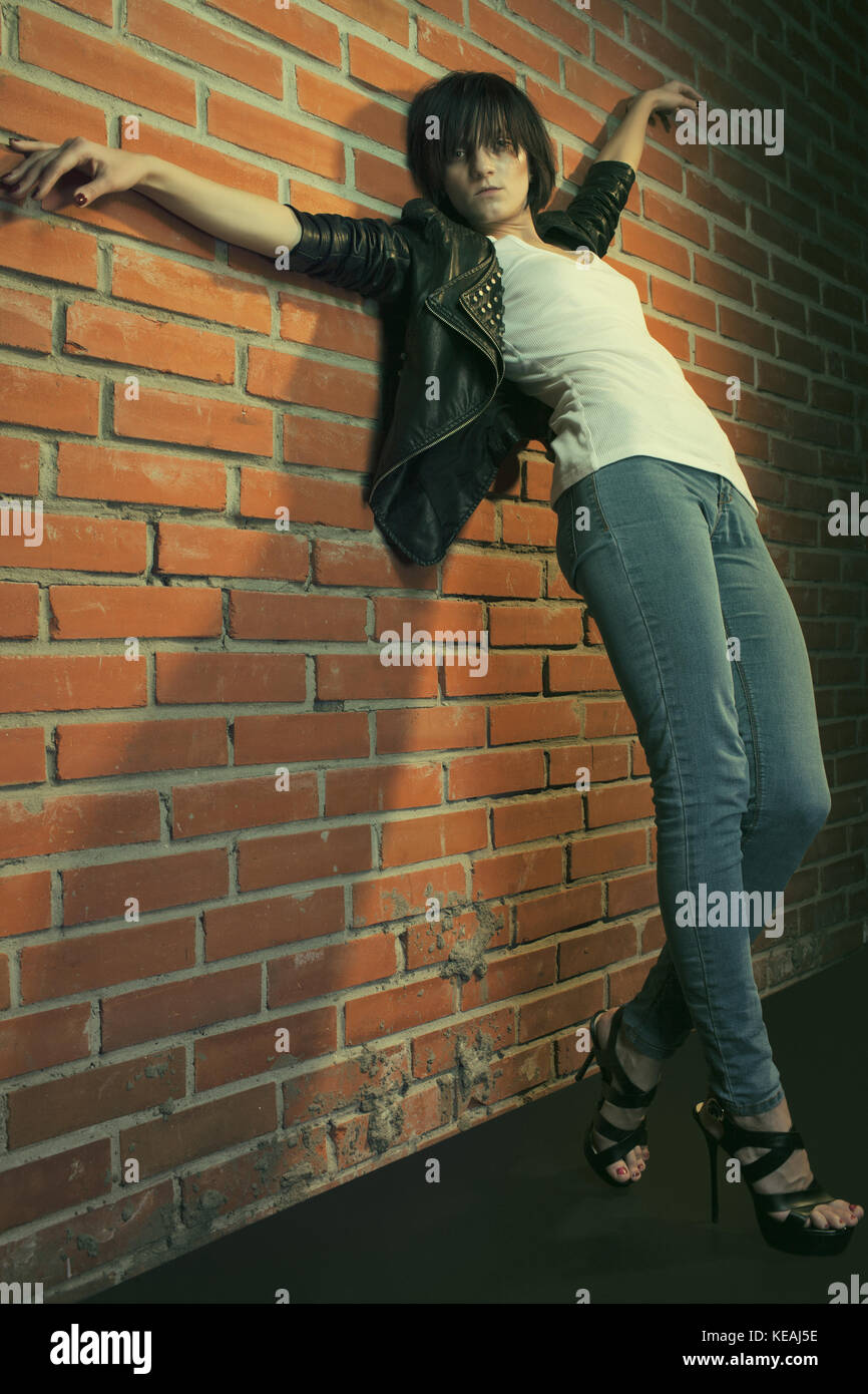 Androgyny female model in Heroin chic style near brick wall. Old style ...