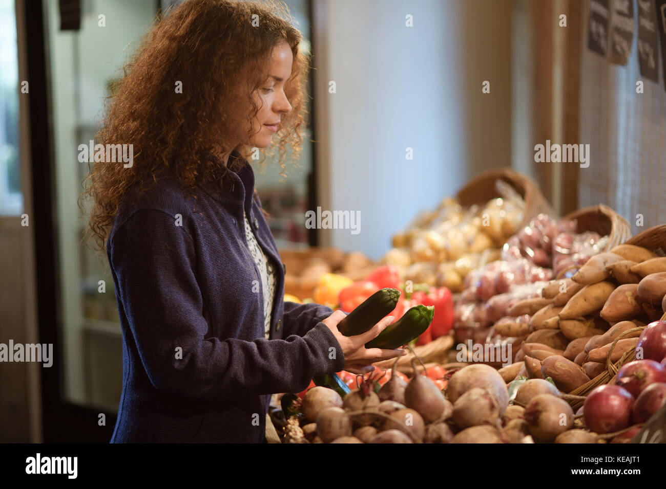 Woman picking fresh produce from a vegetable stall at a farm market ...
