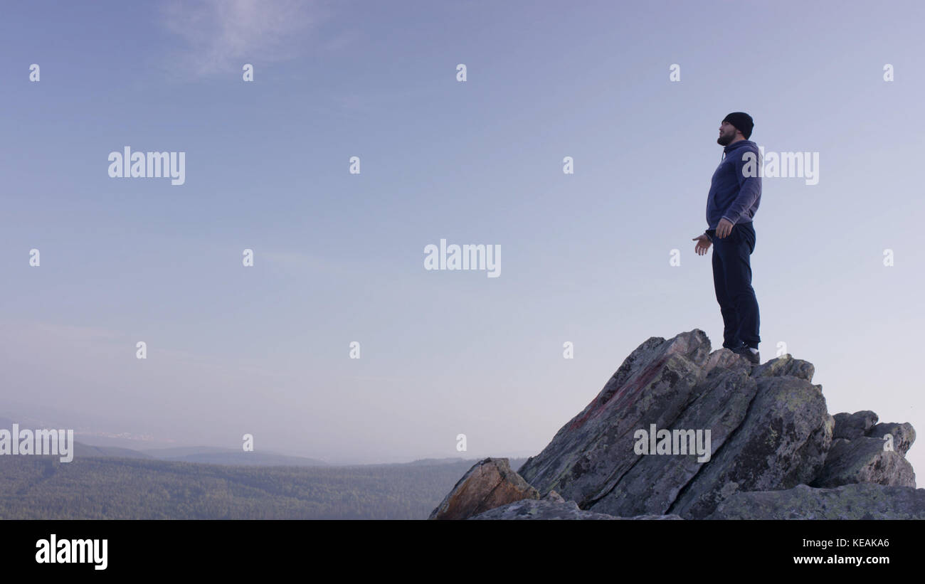 Man on top of the mountain. A young, athletic man stands on a high rock ...