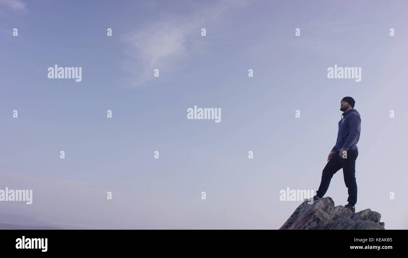 Man on top of the mountain. A young, athletic man stands on a high rock ...