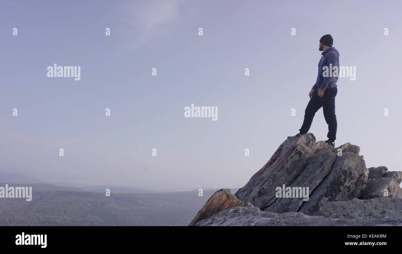 Man on top of the mountain. A young, athletic man stands on a high rock ...