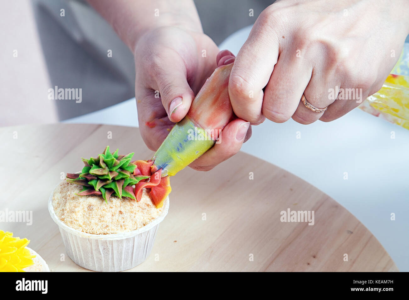 A close-up of a confectioner woman decorates using a pastry syringe and ...
