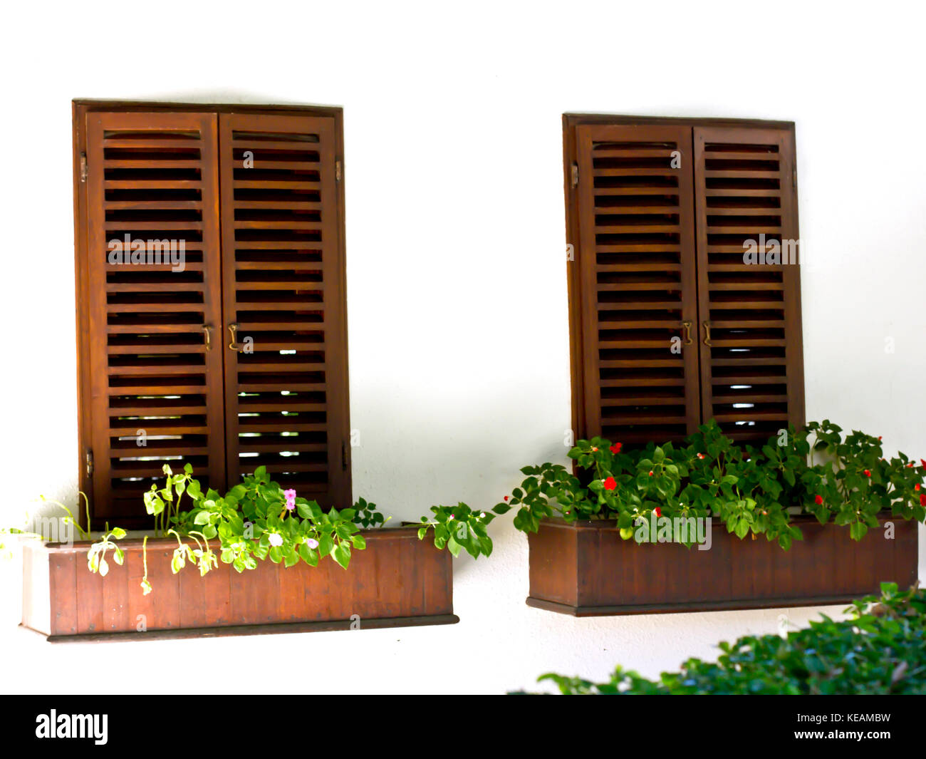 Light wall with the dark brown wooden shutters and wooden boxes with ...