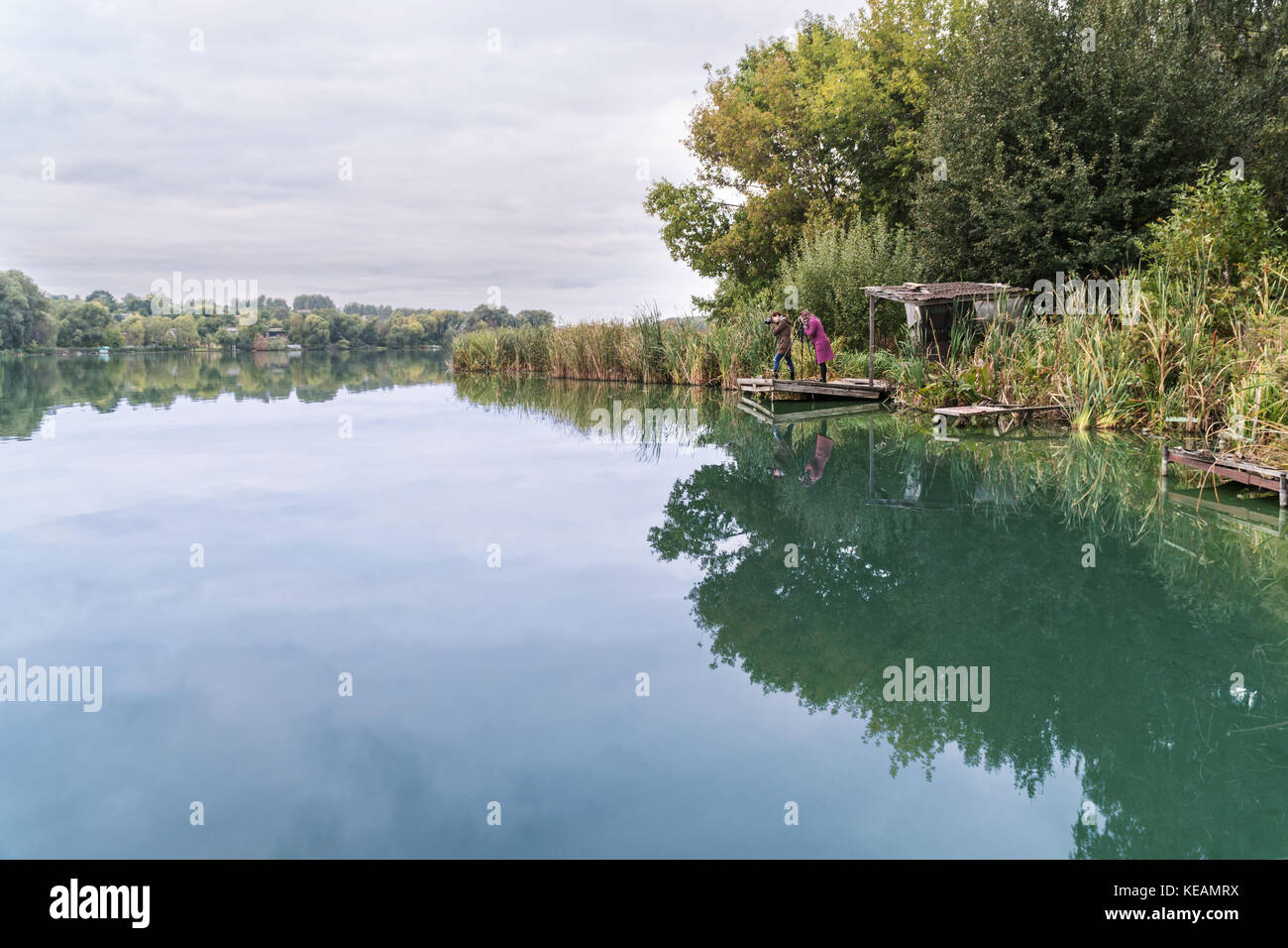 Two women taking pictures of the lake standing on the old wooden ...