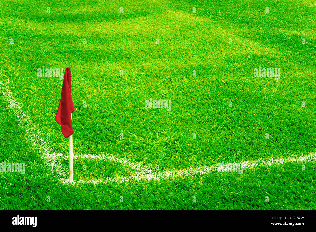 Red corner flag on a football field with bright fresh green turf grass ...