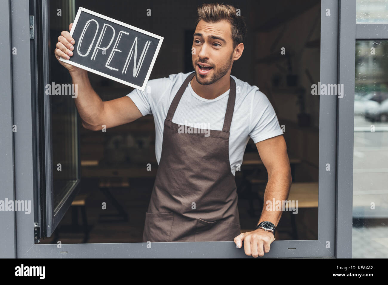 waiter holding chalkboard with open word Stock Photo - Alamy