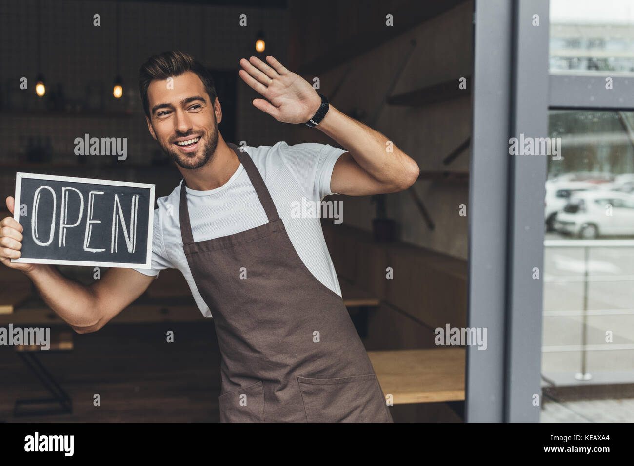 waiter holding chalkboard with open word Stock Photo - Alamy