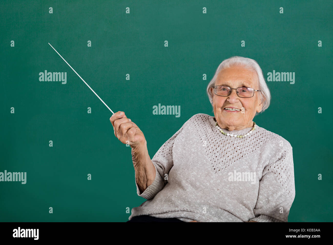 Portrait Of Happy Senior Female Teacher Holding Pointer In Classroom ...