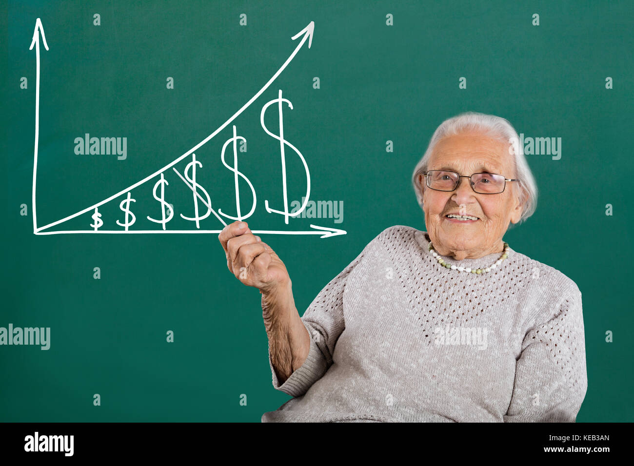 Happy Senior Female Teacher Showing Graph With Pointer On Blackboard ...