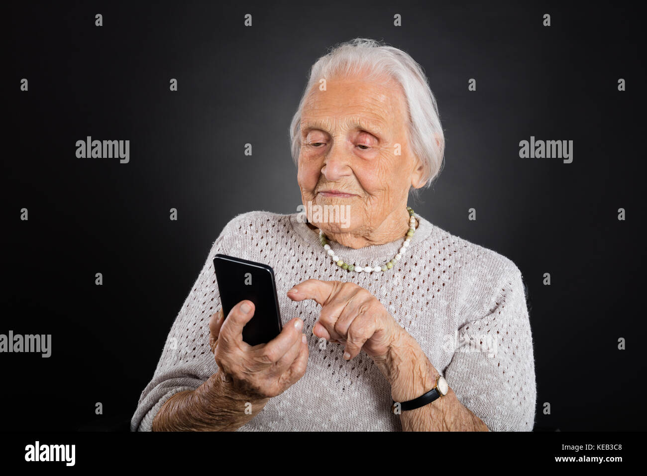 Senior Woman Using Smartphone Over Grey Background Stock Photo - Alamy