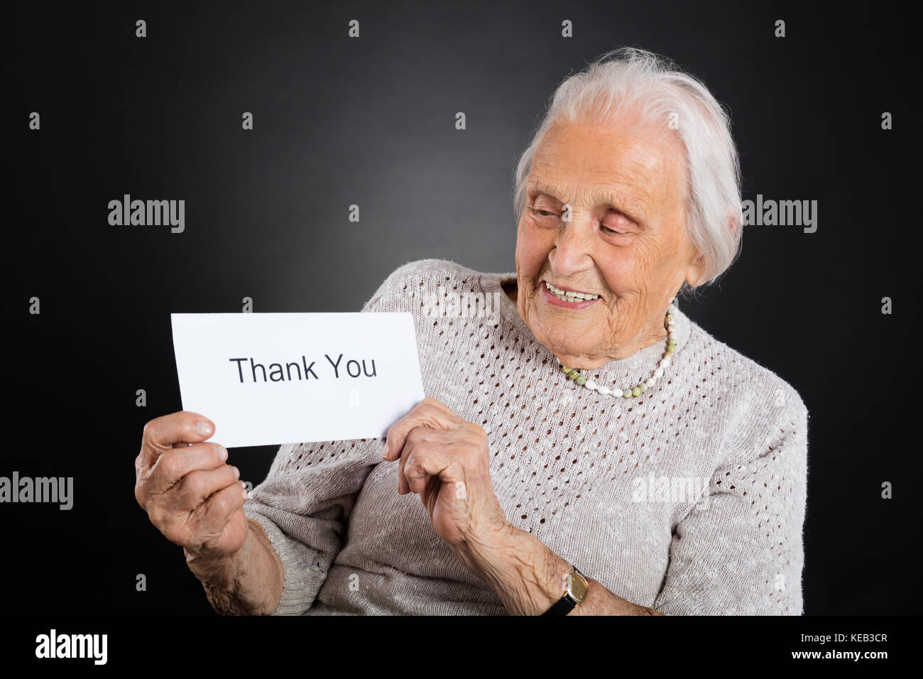 Portrait Of Smiling Elder Woman Showing Thank You Card Over Grey ...