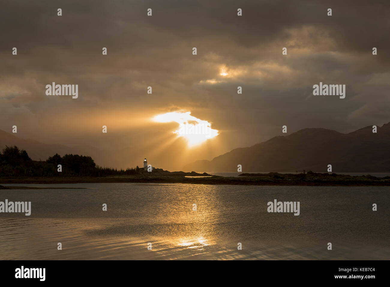 Dramatic dawn light and sunbeams at Ornsay lighthouse on the islet of ...