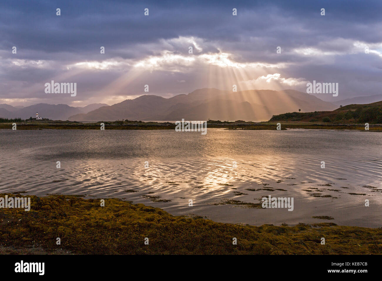 Dramatic dawn light and sunbeams at Ornsay lighthouse on the islet of ...