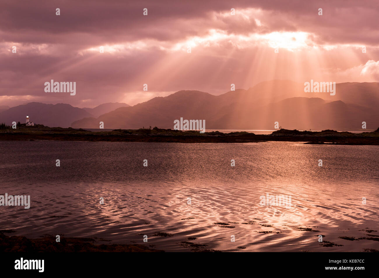 Dramatic dawn light and sunbeams at Ornsay lighthouse on the islet of ...