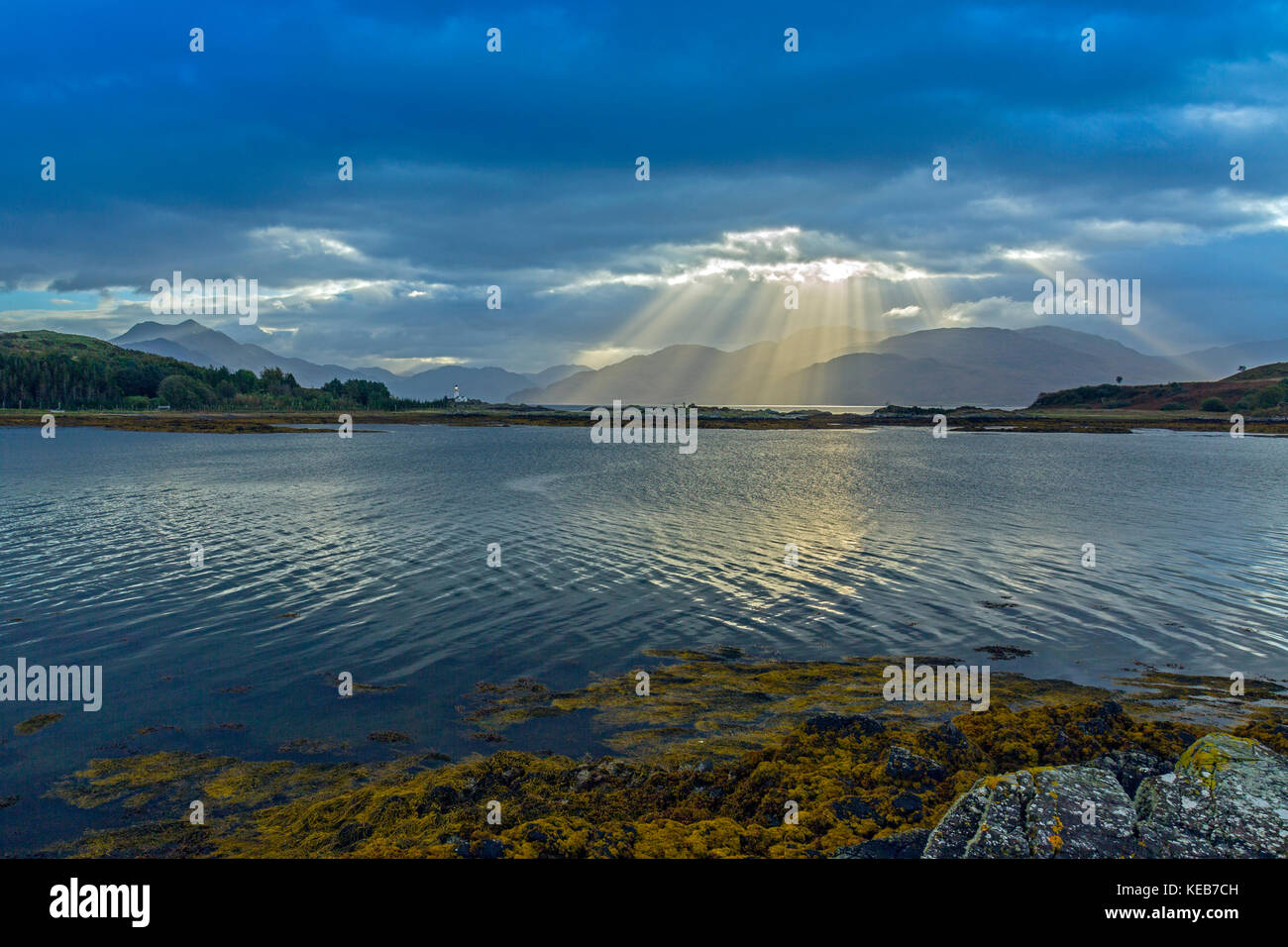 Dramatic dawn light and sunbeams at Ornsay lighthouse on the islet of ...