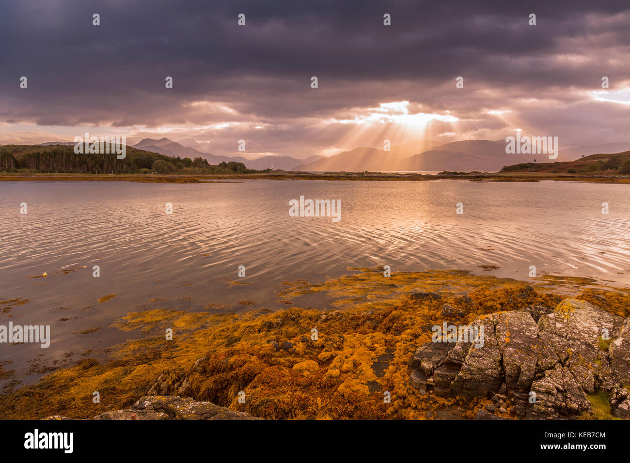 Dramatic dawn light and sunbeams at Ornsay lighthouse on the islet of ...