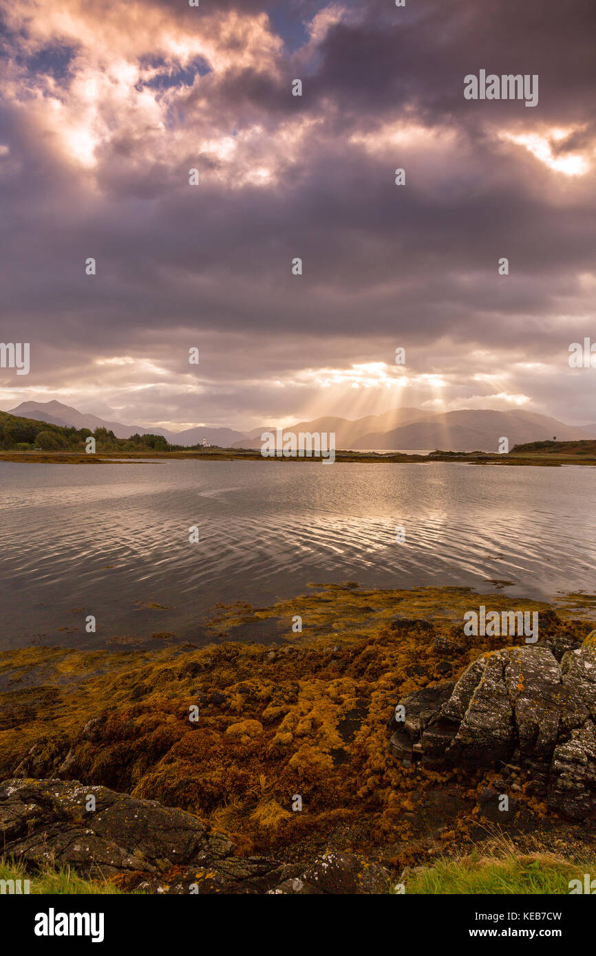 Dramatic dawn light and sunbeams at Ornsay lighthouse on the islet of ...