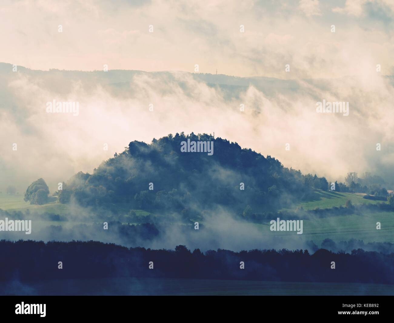 Distant mountain range and heavy clouds of colorful mist above deep ...