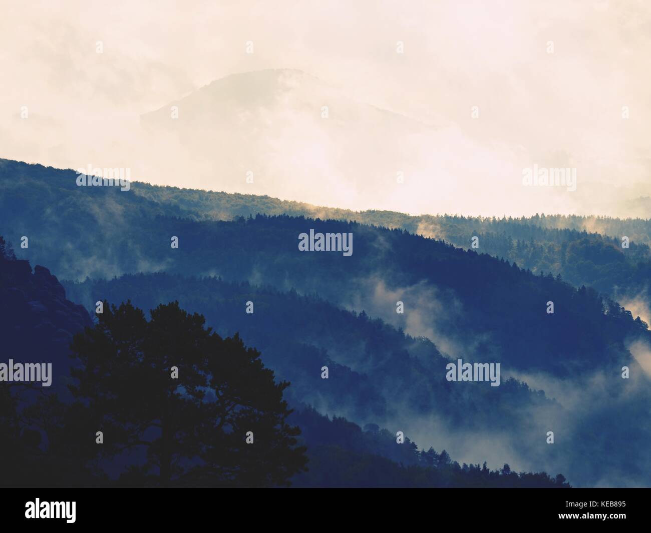 Distant mountain range and heavy clouds of colorful mist above deep ...