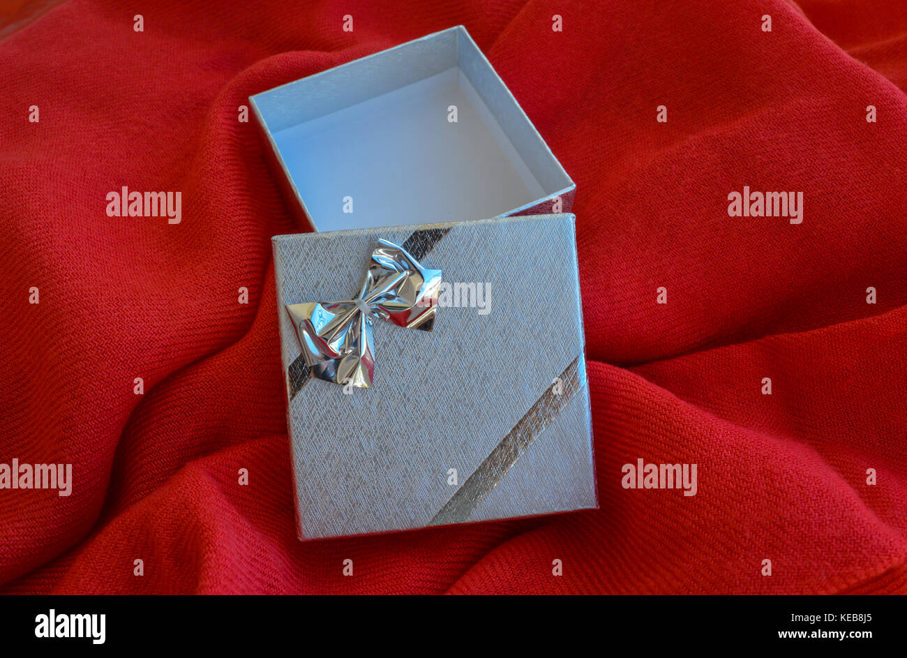 Empty silver gift box on a red fabric background Stock Photo - Alamy
