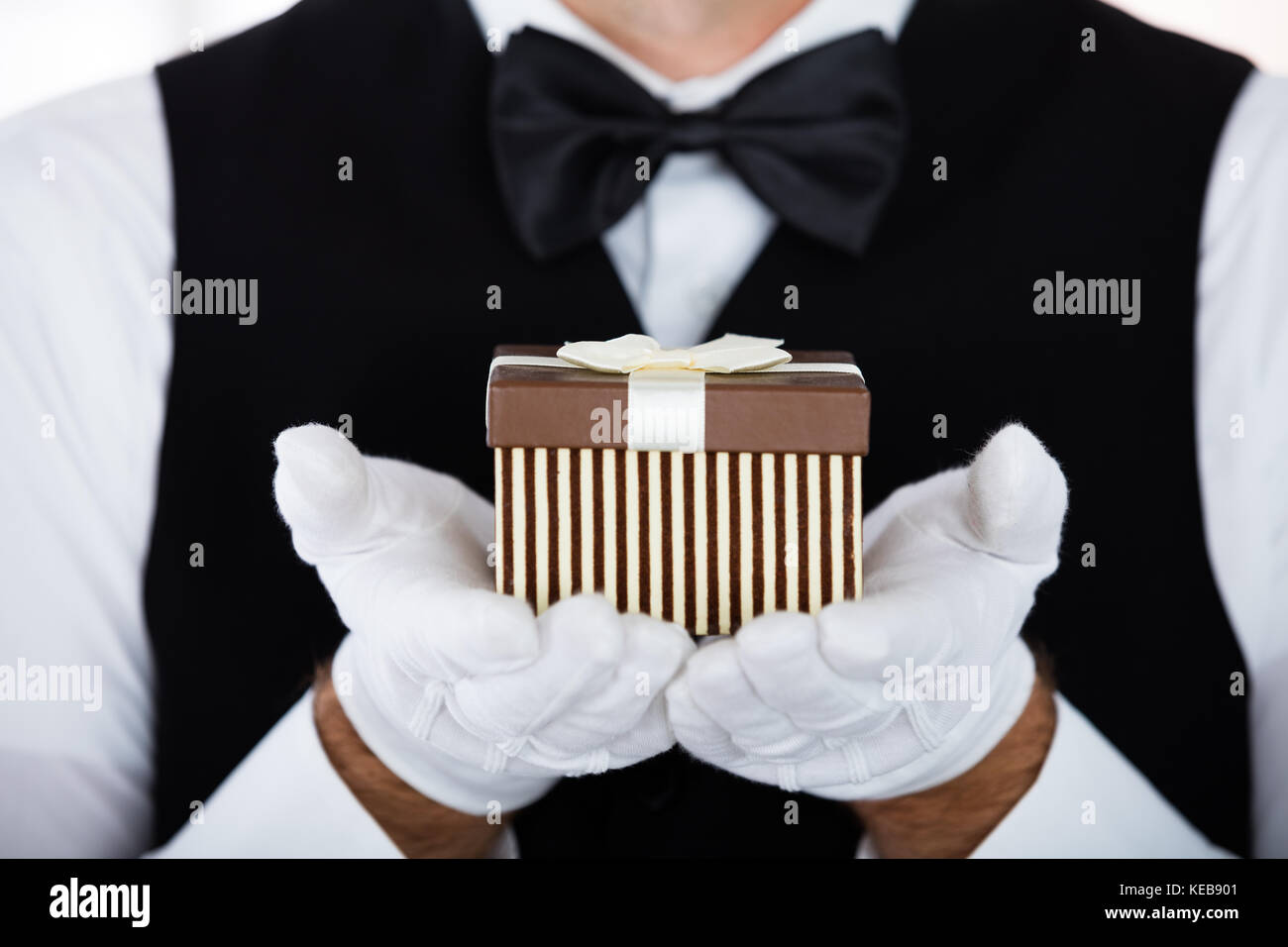 Man Waiter Wearing Bowtie Presenting Small Gift Stock Photo - Alamy