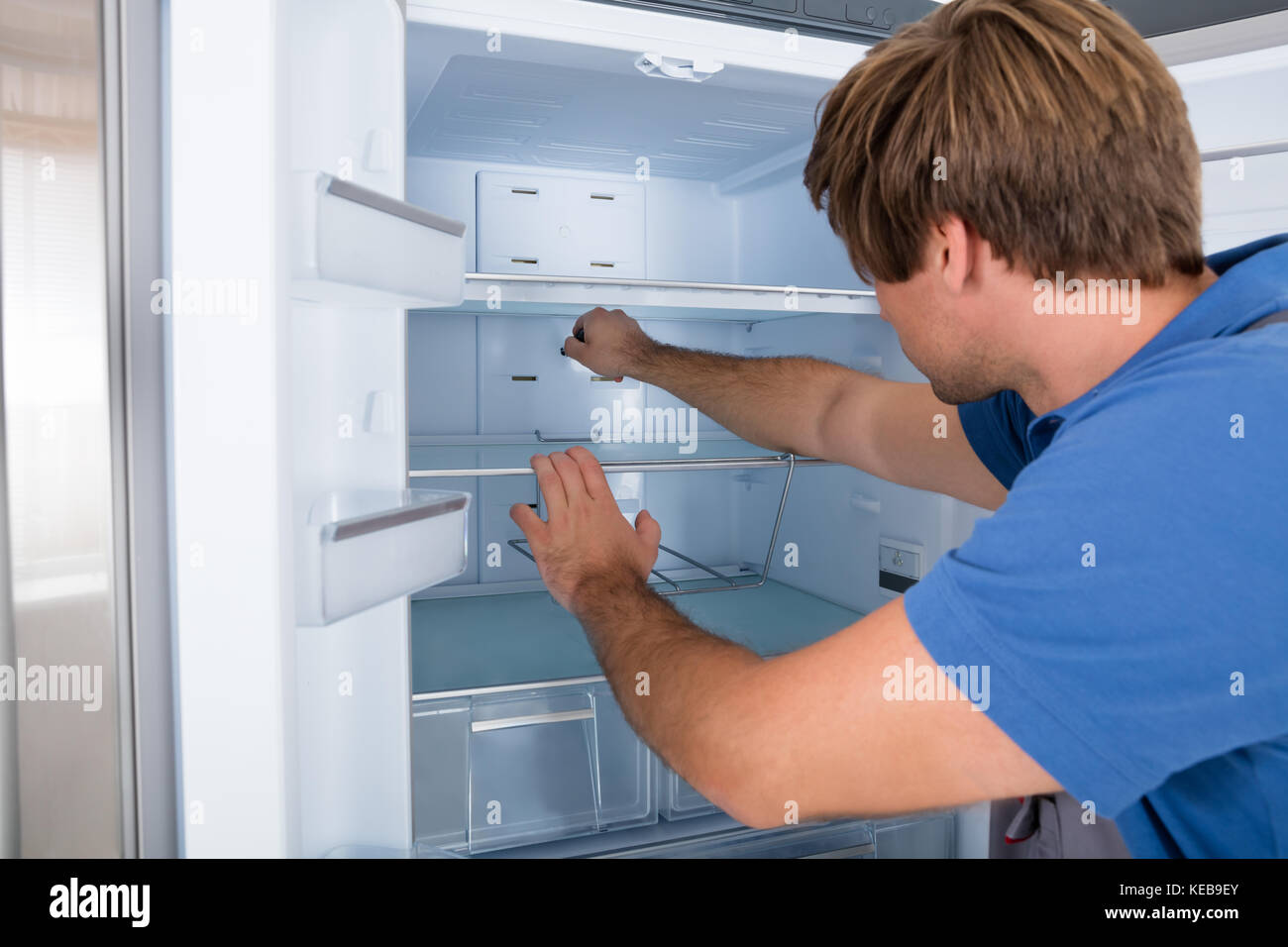 Male Technician Examining Broken Refrigerator Appliance At Home Stock ...