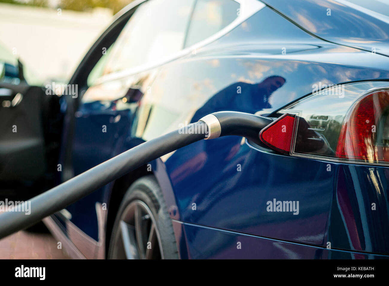 Modern electric blue car plugged to charging station Stock Photo - Alamy