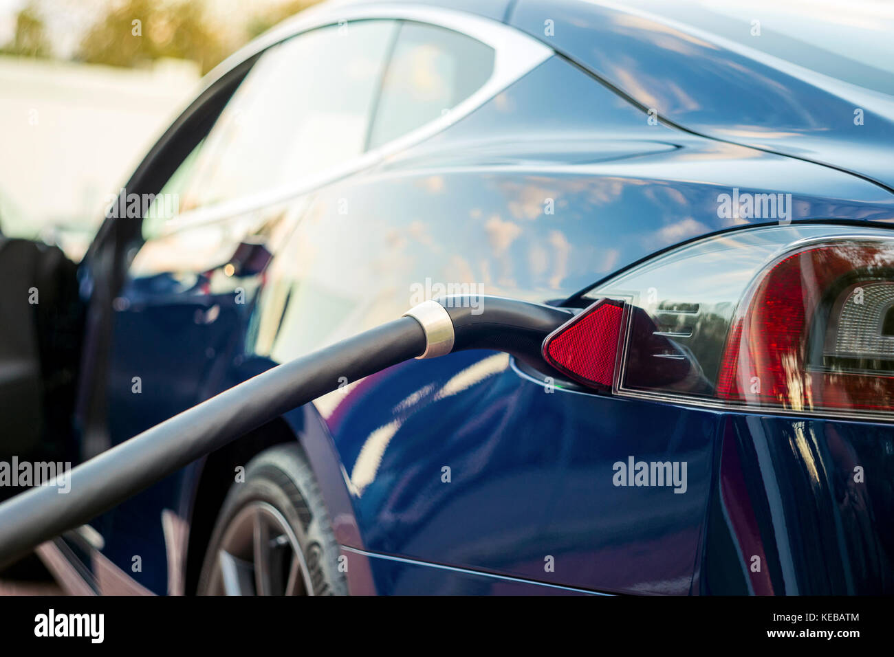 Modern electric blue car plugged to charging station Stock Photo - Alamy