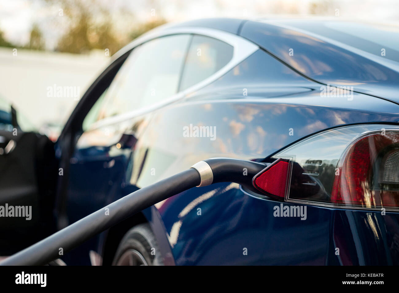 Modern electric blue car plugged to charging station Stock Photo - Alamy