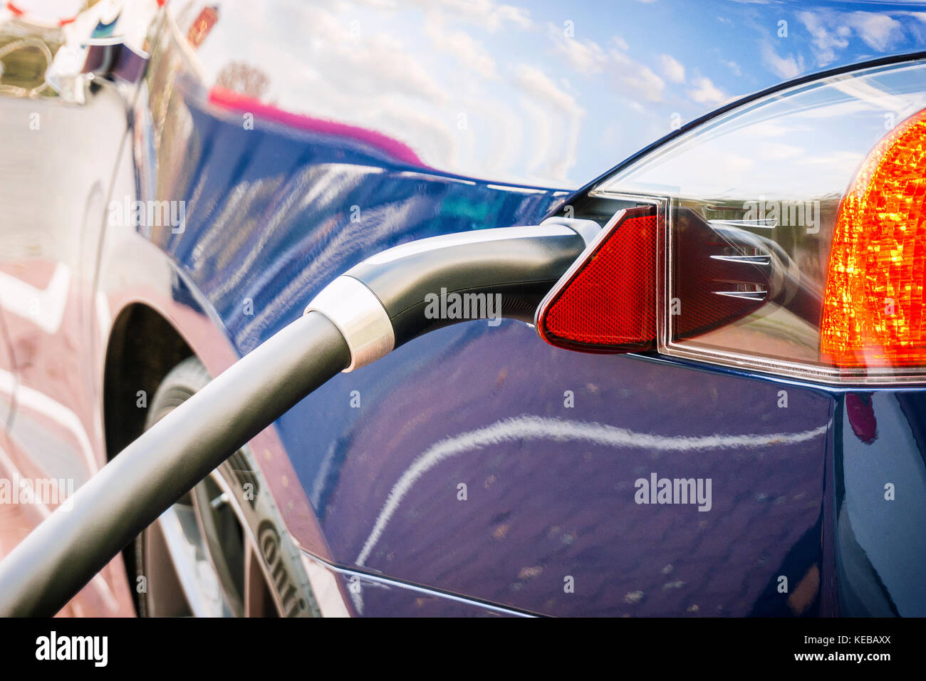 Modern electric blue car plugged to charging station Stock Photo - Alamy