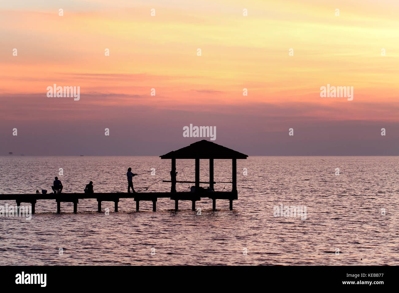 Silhouette image of people fishing at the jetty during sunset Stock ...