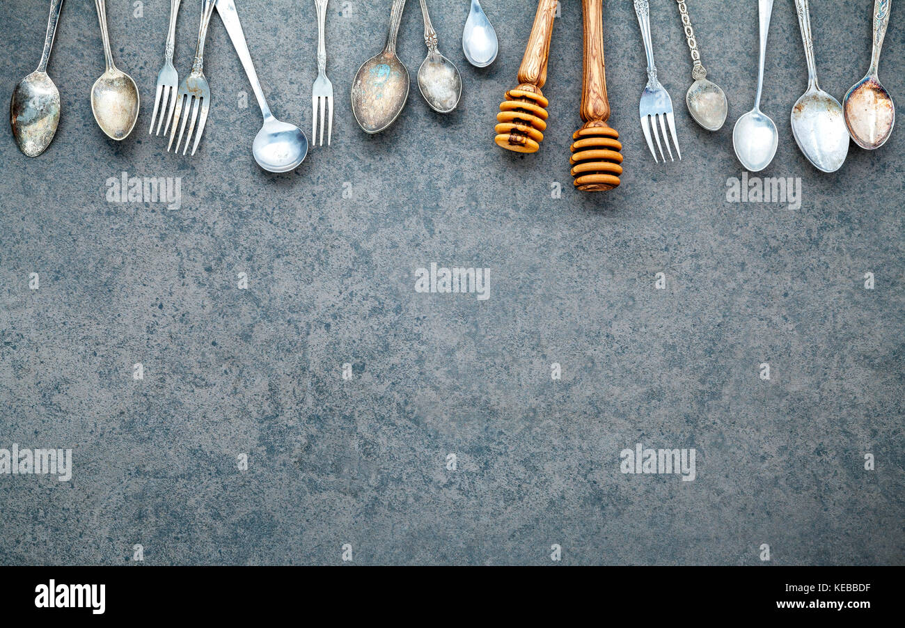 Various cooking utensils border. Spoons and fork on dark stone ...