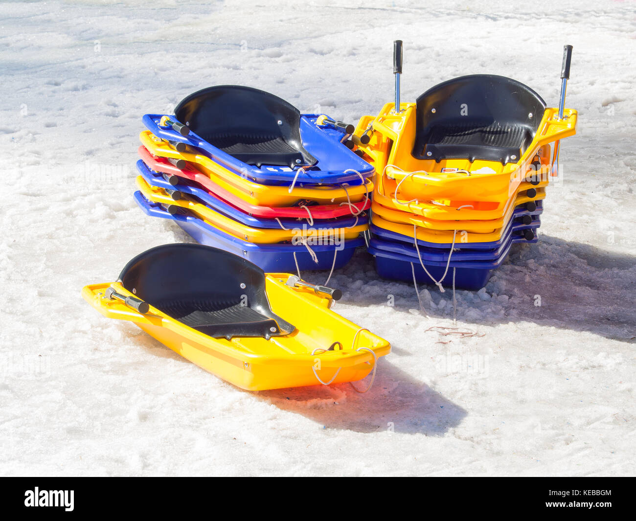 group of colorful toy bobsleigh stacked in the snow waiting for funny ...