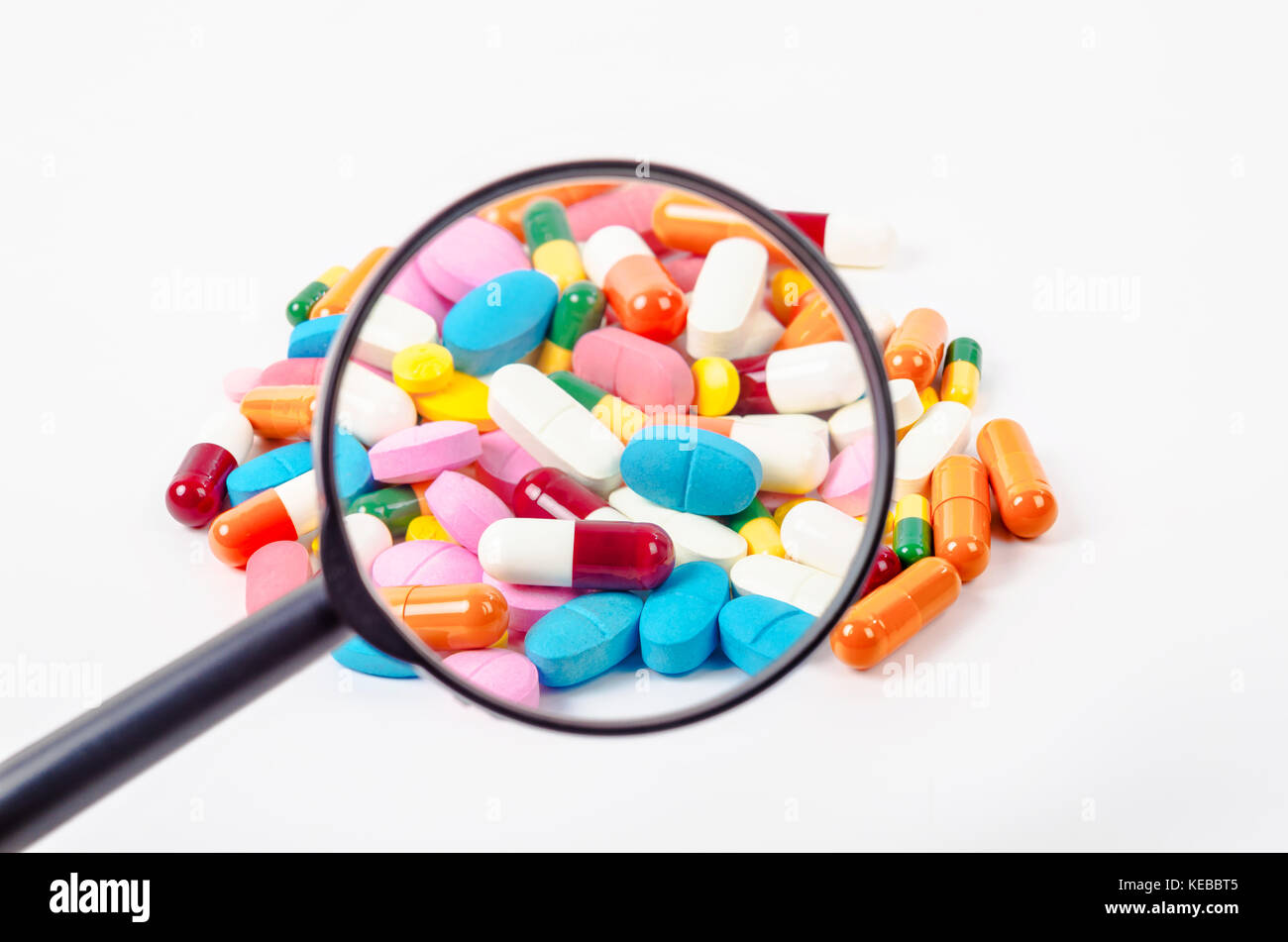 pills under magnifying glass on white background Stock Photo - Alamy
