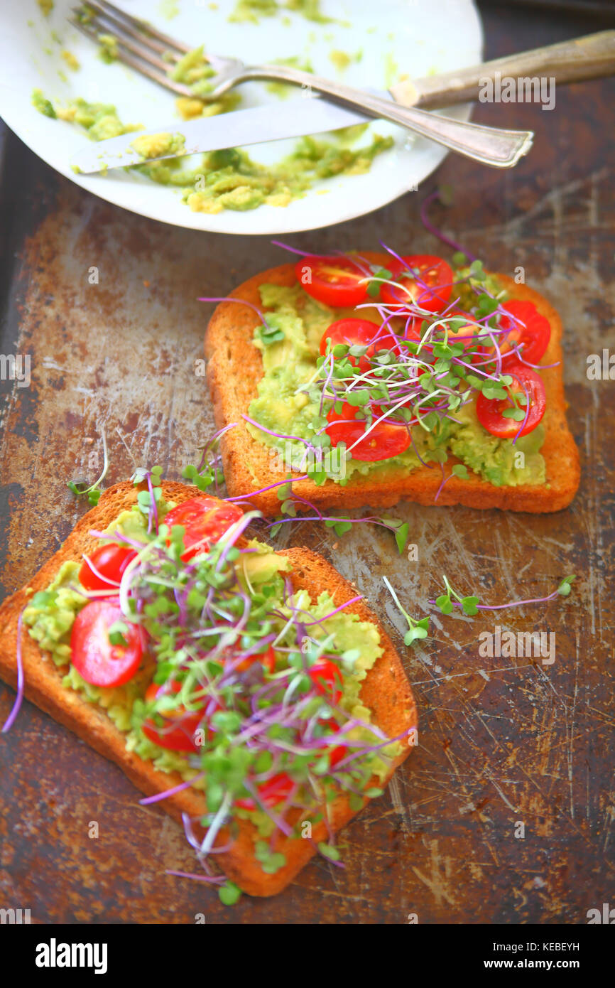 Avocado toast with cherry tomatoes and sprouts on old baking pan Stock ...