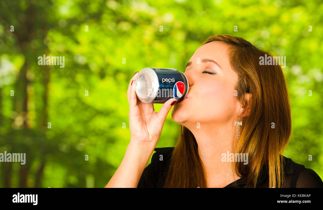Pretty young woman drinking a pepsi in blurred green background Stock ...