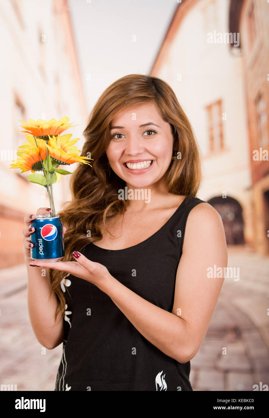Pretty young woman holding a pepsi with sunflowers inside in blurred ...