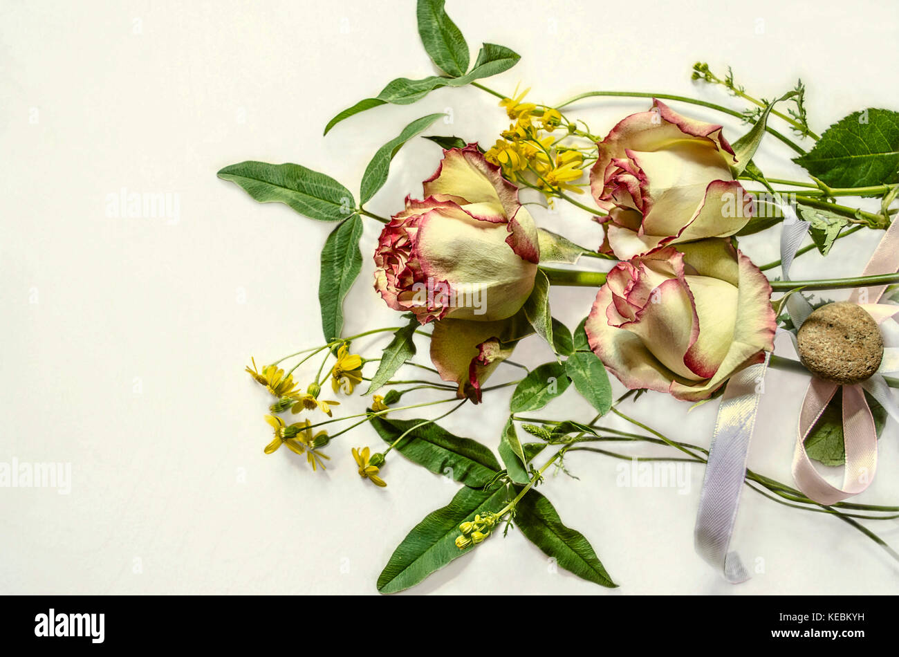 Bouquet of white with pink border roses, wild flowers and clover leaves ...