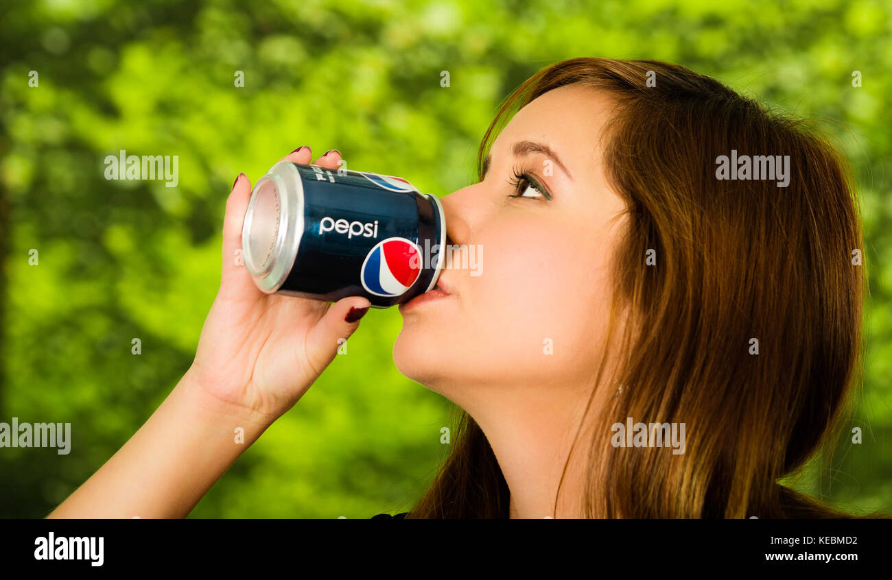 Pretty young woman drinking a pepsi in blurred green background Stock ...