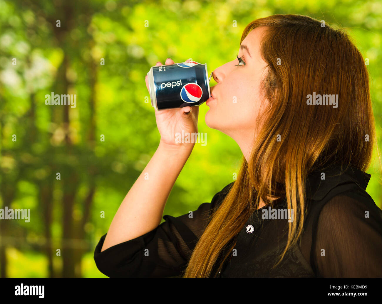 Pretty young woman drinking a pepsi in blurred green background Stock ...