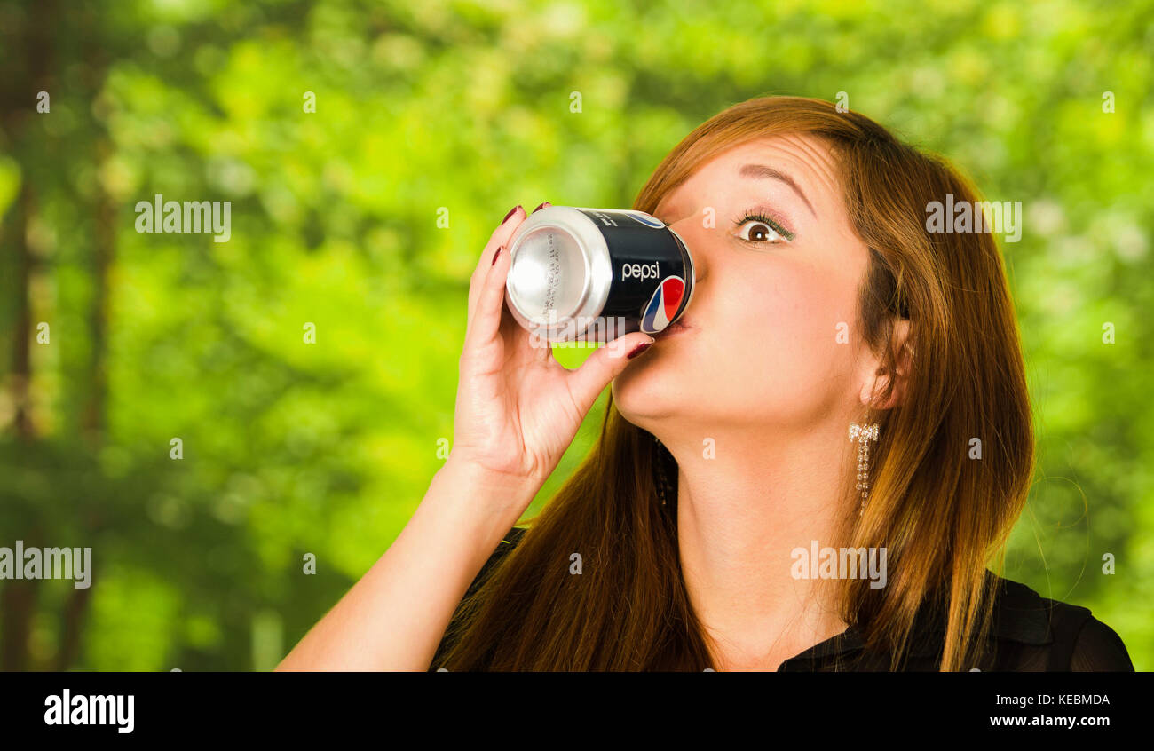 Pretty young woman drinking a pepsi in blurred green background Stock ...
