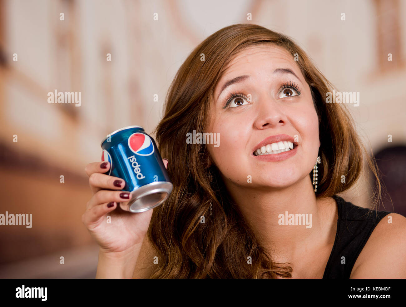 Smiling young woman holding a pepsi in blurred city background Stock ...
