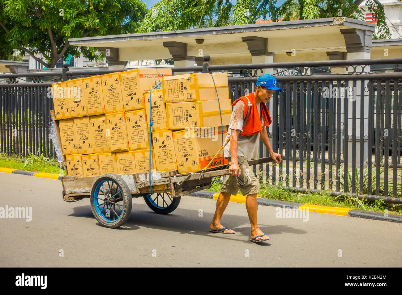 JAKARTA, INDONESIA - 3 MARCH, 2017: Local working man pulling trolley ...