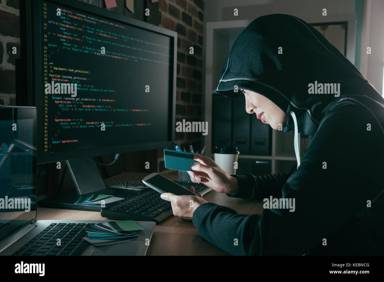 evil smiling hacker holding credit card and mobile smartphone ready for ...