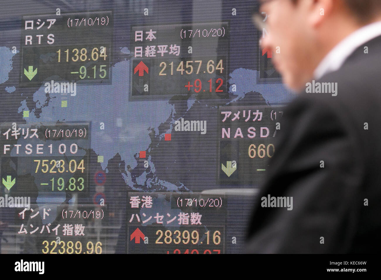 A man walks past an electronic stock board showing Japan's Nikkei Stock ...