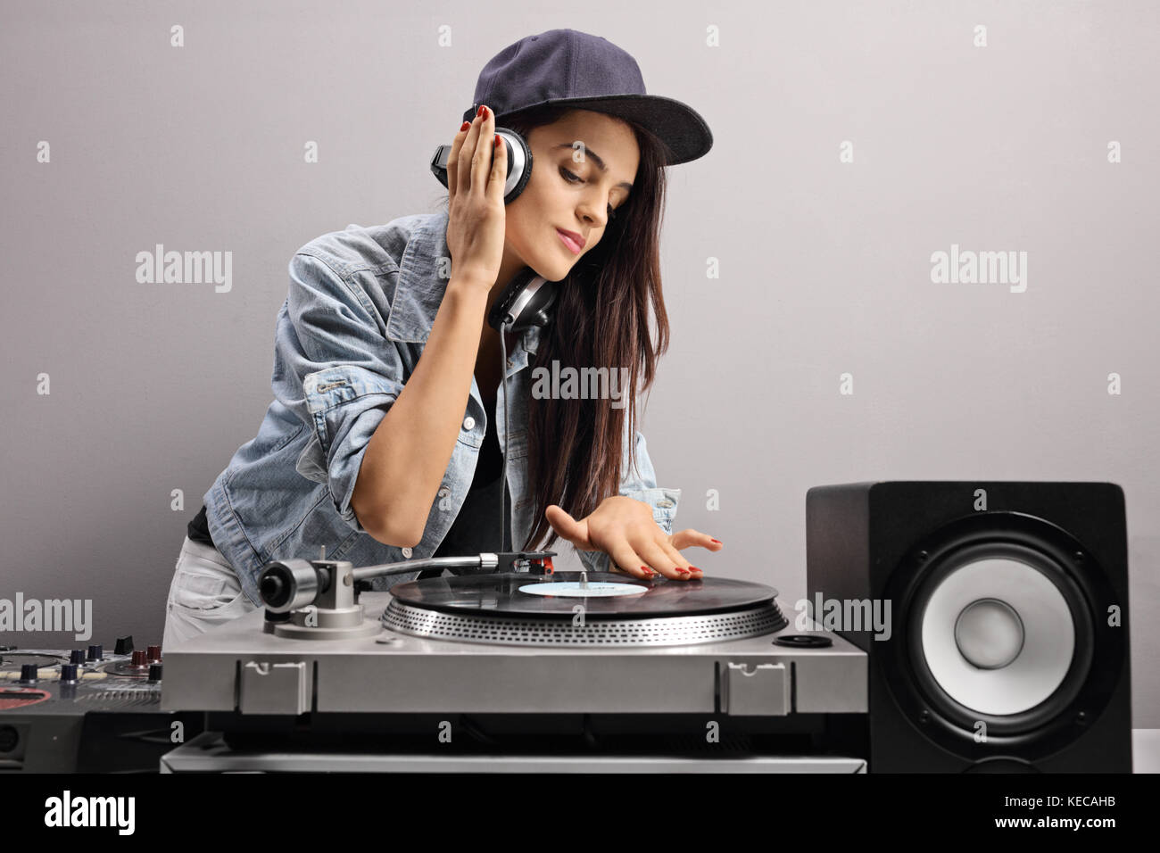 Female DJ playing music on a turntable against a gray wall Stock Photo ...